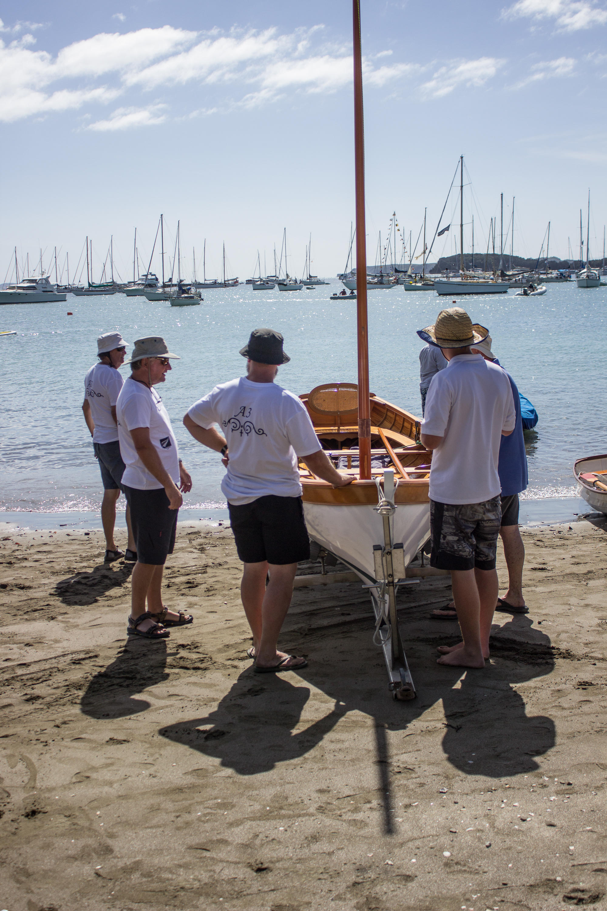 Photograph: Group of people standing next to a sailing dinghy on a ...