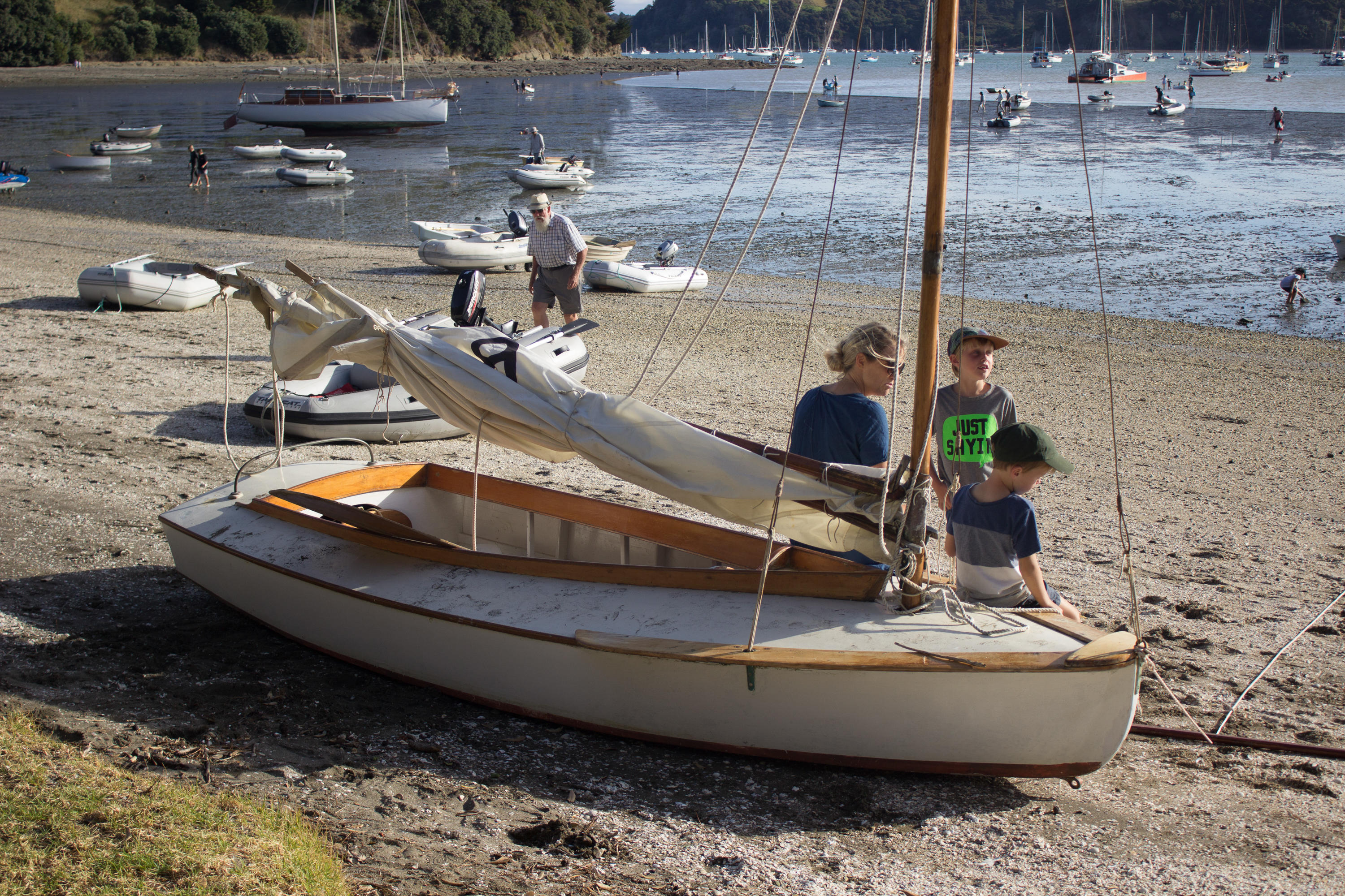 Photograph: People beside a sailing dinghy on beach, Mahurangi Harbour ...