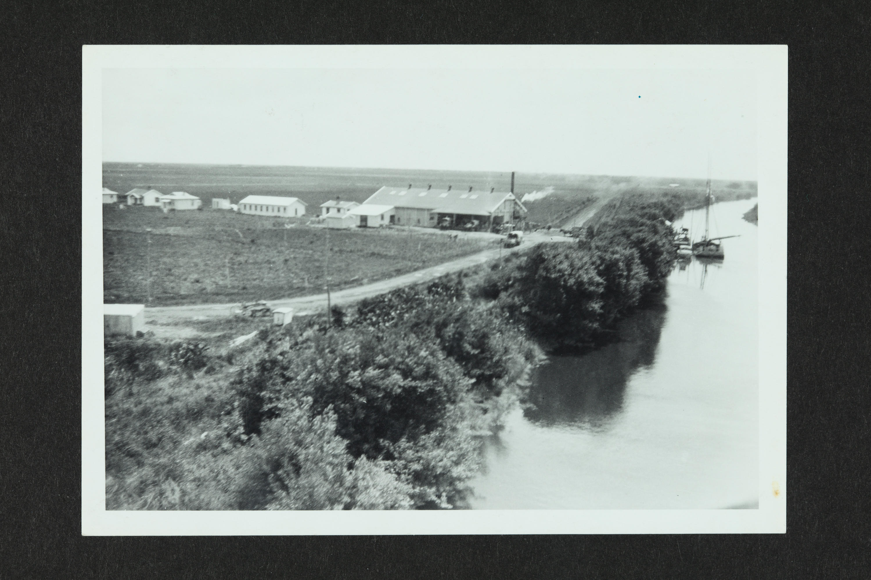 Photograph: View from unidentified vessel across farmland and wharf ...